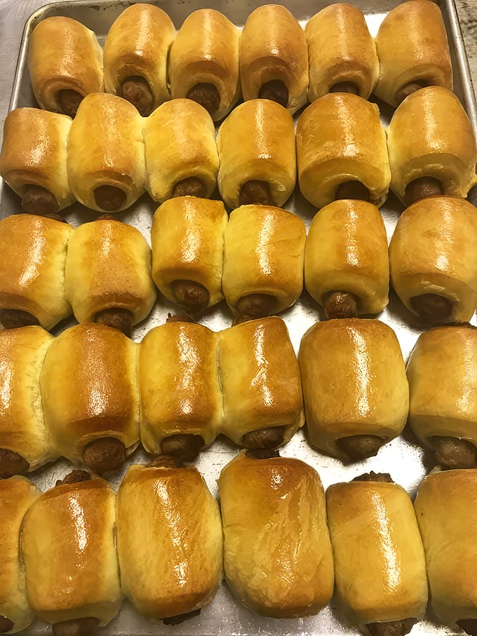 Pigs-in-blankets lined up like delicious little soldiers. These golden-brown bundles of joy prove that sausage and potato flour were destined to be together.