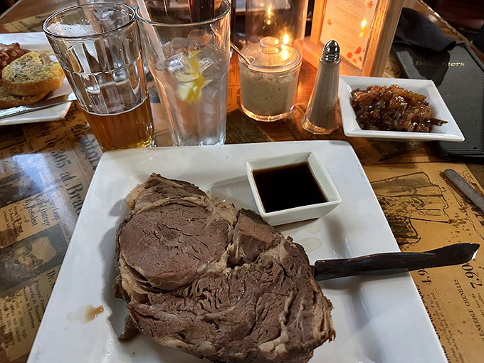 The King Cut prime rib arrives like royalty on a white plate throne, accompanied by its loyal subject: a humble baked potato in full regalia.