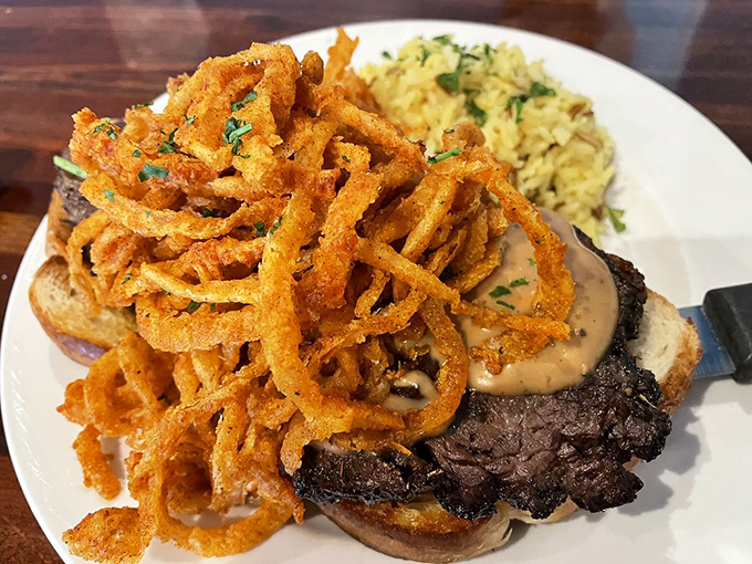 This steak sandwich topped with crispy onion straws isn't just a meal&mdash;it's architecture you can eat. Savory skyscraper of flavor.
