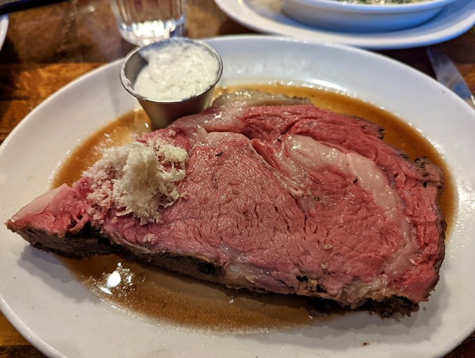 A slice of prime rib heaven bathed in au jus with horseradish cream standing by. The perfect marriage of tenderness and flavor in its natural habitat.