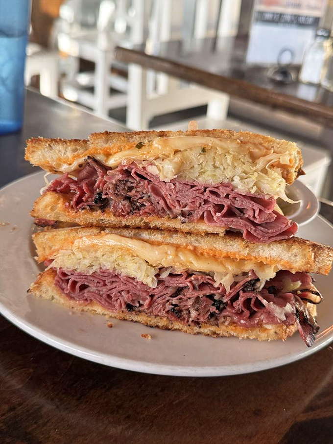 The cross-section reveals the sandwich's soul&mdash;layers of pink corned beef nestled with sauerkraut and melted Swiss. This isn't lunch; it's edible poetry.