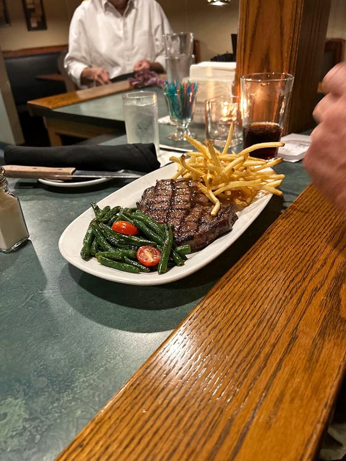 A perfectly seared steak flanked by crispy fries and vibrant green beans &ndash; the holy trinity of steakhouse satisfaction.