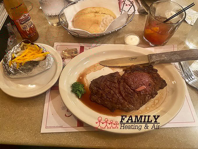 A steak that demands your full attention, a baked potato wrapped in foil like a precious gift, and those dinner rolls that grandmothers everywhere would approve of.