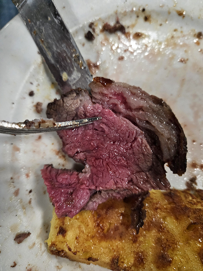 The knife reveals the steak's inner soul—a perfect medium-rare gradient that would make even the most stoic butcher shed a tear of pride.