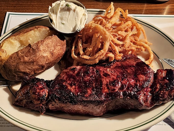 The Pine Club's strip steak arrives with a textbook-perfect crust, alongside a loaded baked potato and those legendary onion rings.