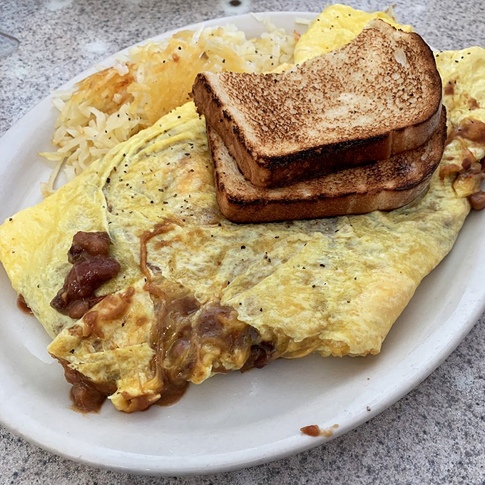 This omelet doesn't just satisfy hunger&mdash;it tells a story of perfectly folded eggs embracing melted cheese and crispy hash browns with toast standing by.