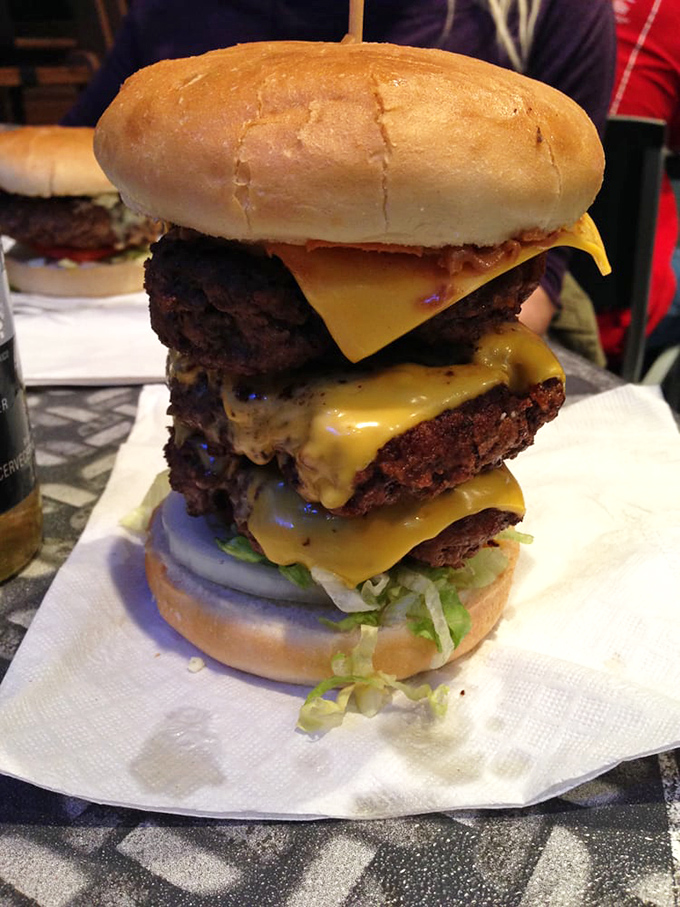 The Triple Cheeseburger: where physics-defying height meets mouth-watering flavor in a tower of beef that requires strategic eating plans.