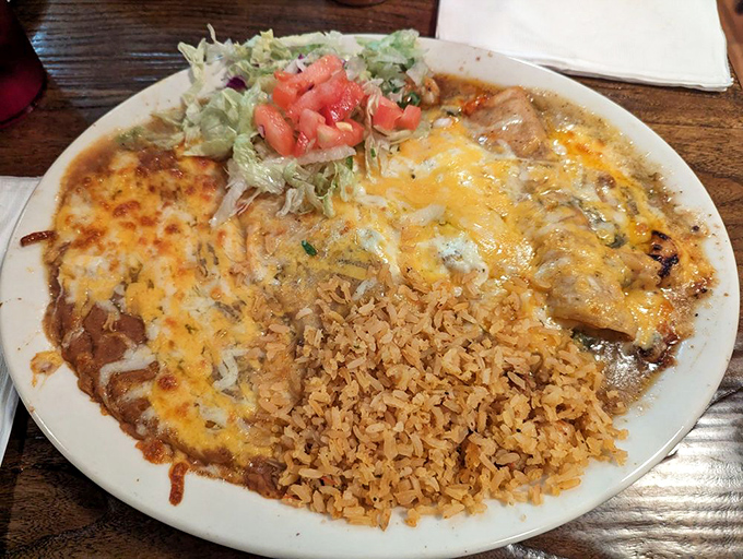 The holy trinity of Mexican comfort: shrimp enchiladas, perfectly seasoned rice, and beans that could make your grandmother jealous.