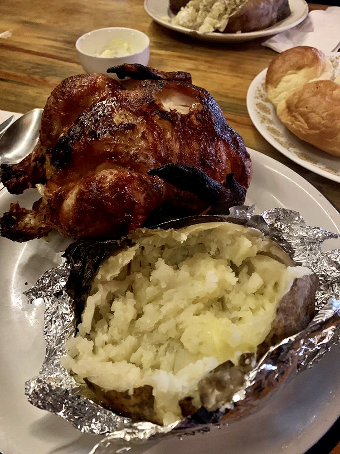 The whole roasted chicken arrives like a centerpiece at Thanksgiving, accompanied by a foil-wrapped potato that could feed a small family.