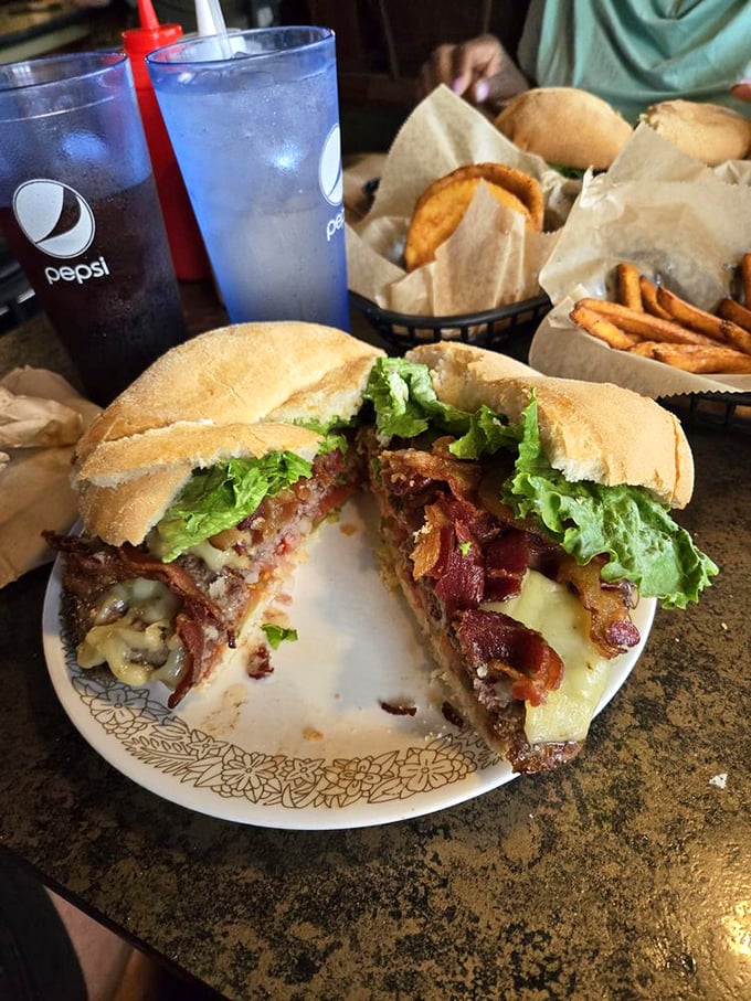 Architecture students, take note: this towering burger demonstrates structural integrity that would make Frank Lloyd Wright weep with joy. Skyscrapers of flavor require toothpicks as support beams.