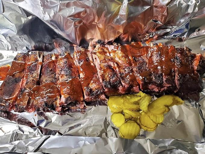 Barbecue artistry at its finest: a rack of ribs with that perfect smoke ring and a side of pickles for that essential tang.