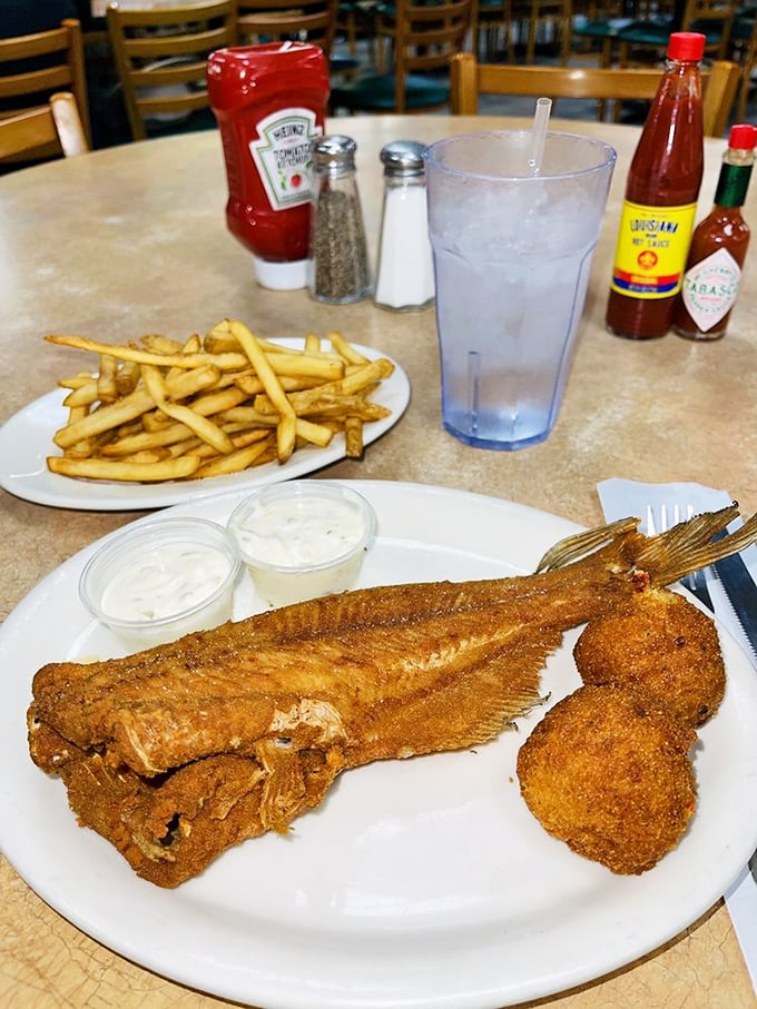 This isn't just fried fish&mdash;it's edible architecture. A perfectly bronzed catfish with hushpuppies standing guard like delicious sentinels.