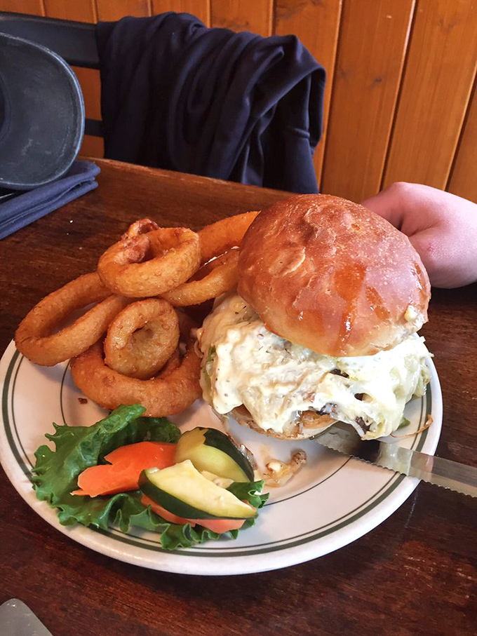 Behold the burger in all its glory&mdash;a towering masterpiece with onion rings as its crown. Your diet plan just called to say it's taking the day off.