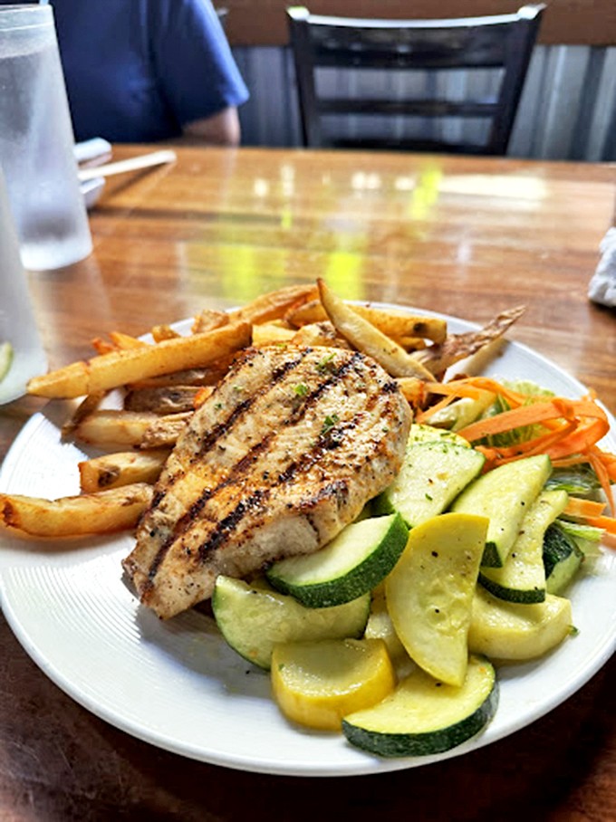 A perfectly grilled fish fillet accompanied by seasonal vegetables and hand-cut fries. This plate demonstrates that sometimes the best seafood preparations let the ocean's bounty speak for itself.