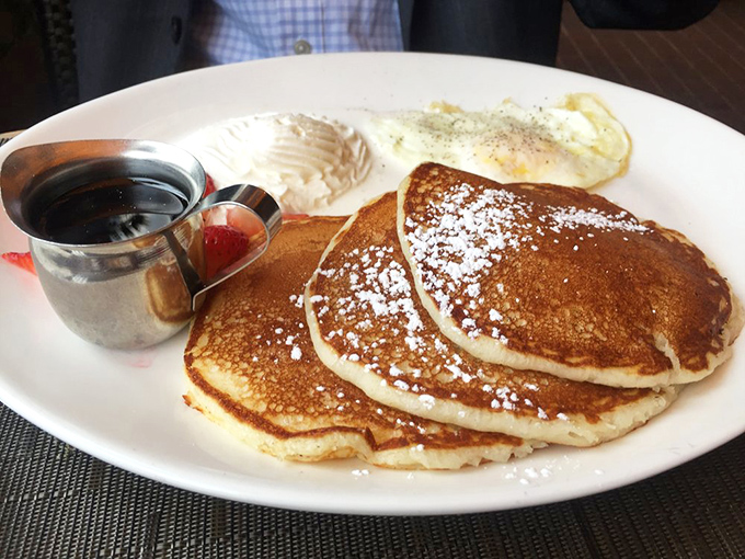 Golden pancakes dusted with powdered sugar alongside perfectly fried eggs—breakfast's greatest hits album on a single plate.