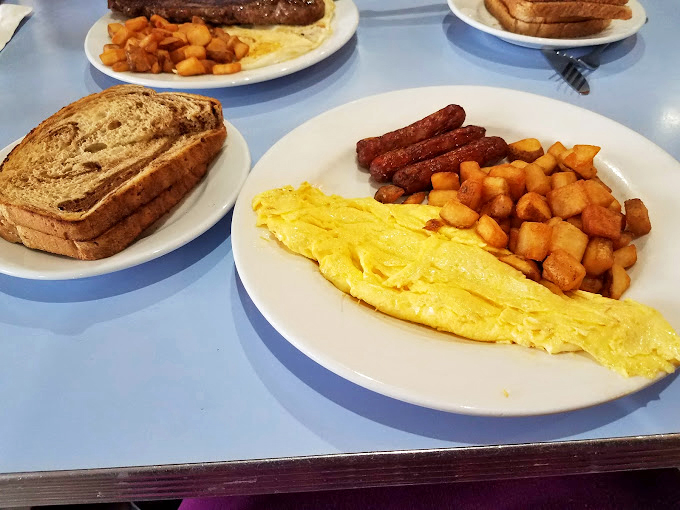 The breakfast trinity: perfectly folded eggs, sausage links standing at attention, and home fries that could make a potato farmer weep with pride.