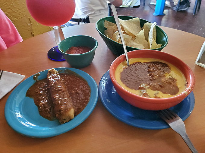 A perfect marriage: the enchilada bathing in rich chili con carne while its companion, a bowl of queso, waits patiently for chip introductions.