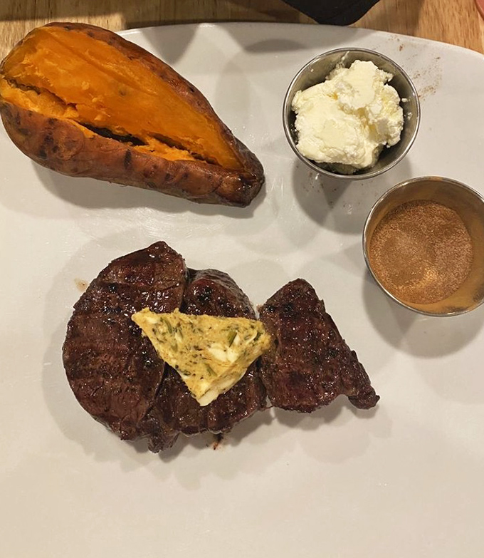 A filet mignon alongside a sweet potato and garlic herb butter&mdash;proof that simplicity executed with precision creates the most memorable dining experiences.