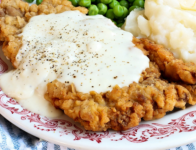 Behold the crown jewel&mdash;country fried steak with its crispy armor and tender interior, baptized in creamy gravy. Mashed potatoes and peas stand by as worthy companions.