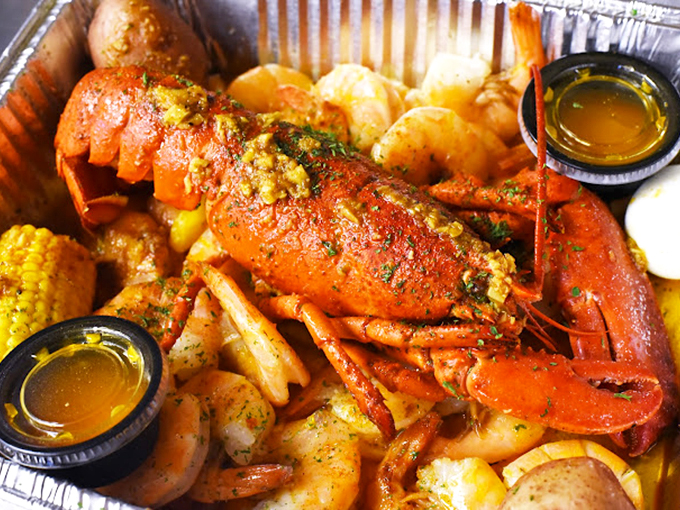 The lobster arrives like royalty on a throne of potatoes and corn, wearing its spice-dusted coat with the confidence of a Broadway star.