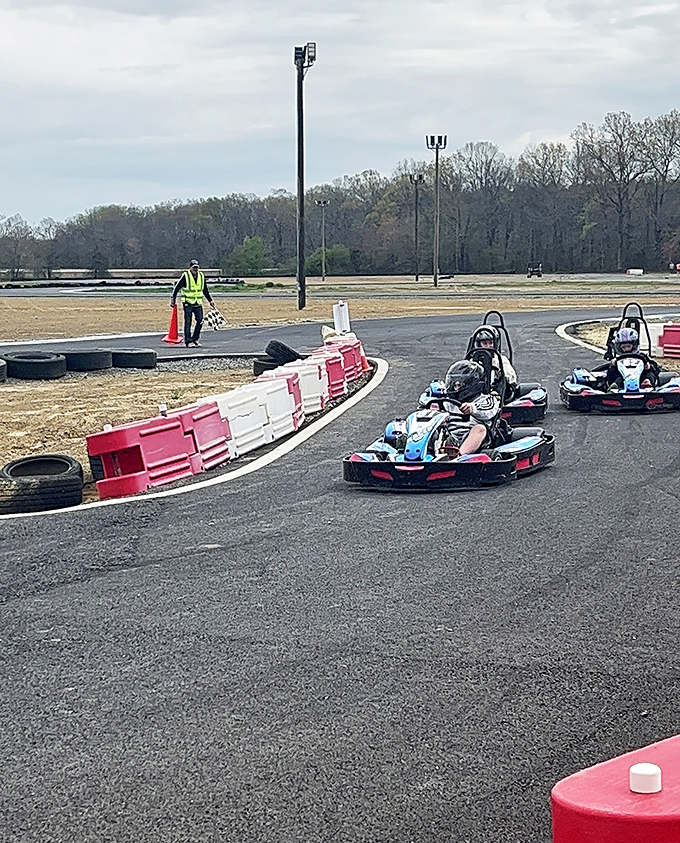The starting grid comes alive as racers prepare for battle. That safety vest isn't just fashion&mdash;it's the universal sign for "I'm in charge of your fun."