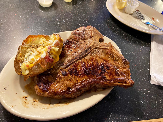 The T-bone arrives like a meat monument, accompanied by a loaded potato that's dressed for its own special occasion. This isn't dinner; it's a celebration.