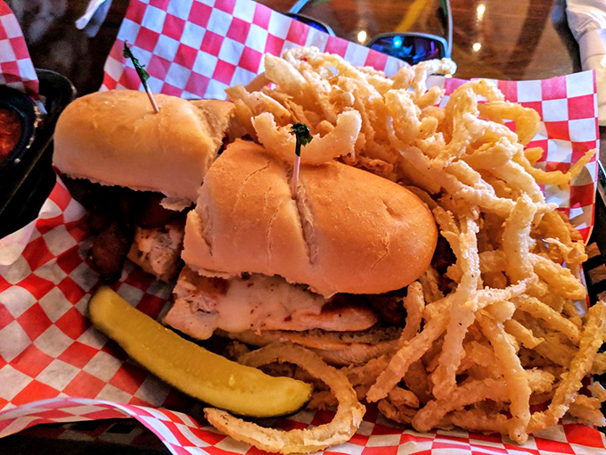 This isn't just a sandwich&mdash;it's an engineering marvel. Crispy onion strings cascade like a waterfall alongside a pickle spear sentinel.