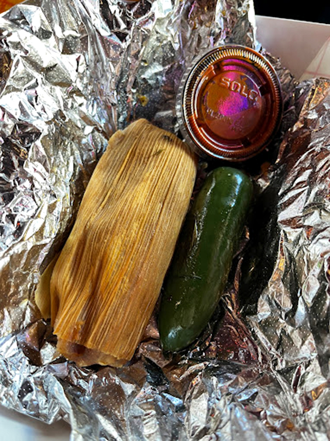 The star of the show: a perfect tamale nestled in foil with its jalape&ntilde;o sidekick. This corn husk-wrapped treasure is worth crossing state lines for.