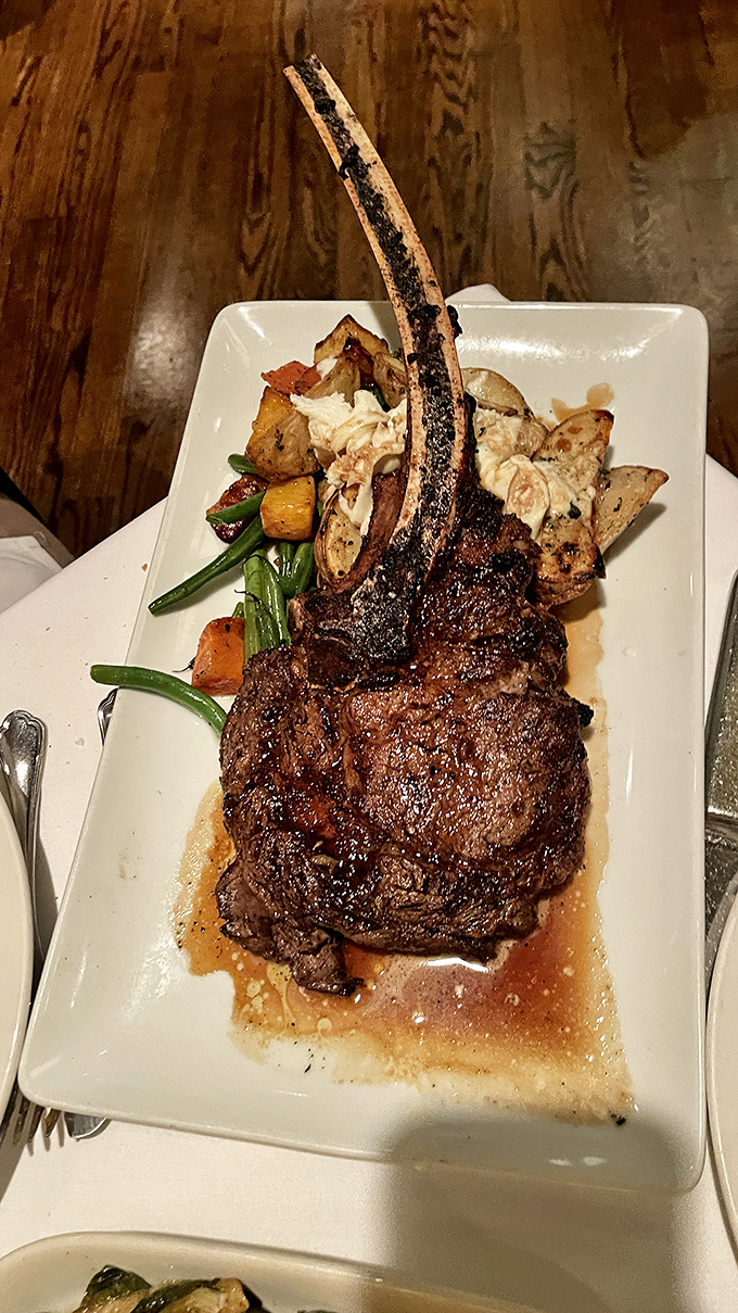 The tomahawk arrives like prehistoric royalty, commanding the table's attention with its dramatic bone and perfectly caramelized exterior.