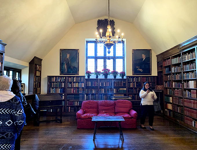 The upstairs library, where portraits of the past watch over modern visitors exploring this literary sanctuary with its inviting crimson sofa.