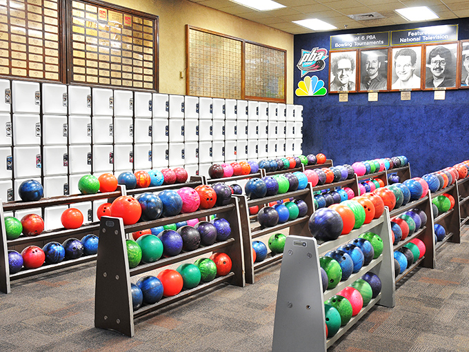 A wall of bowling history watches over the colorful array of balls, silently judging your form like disapproving ancestors.