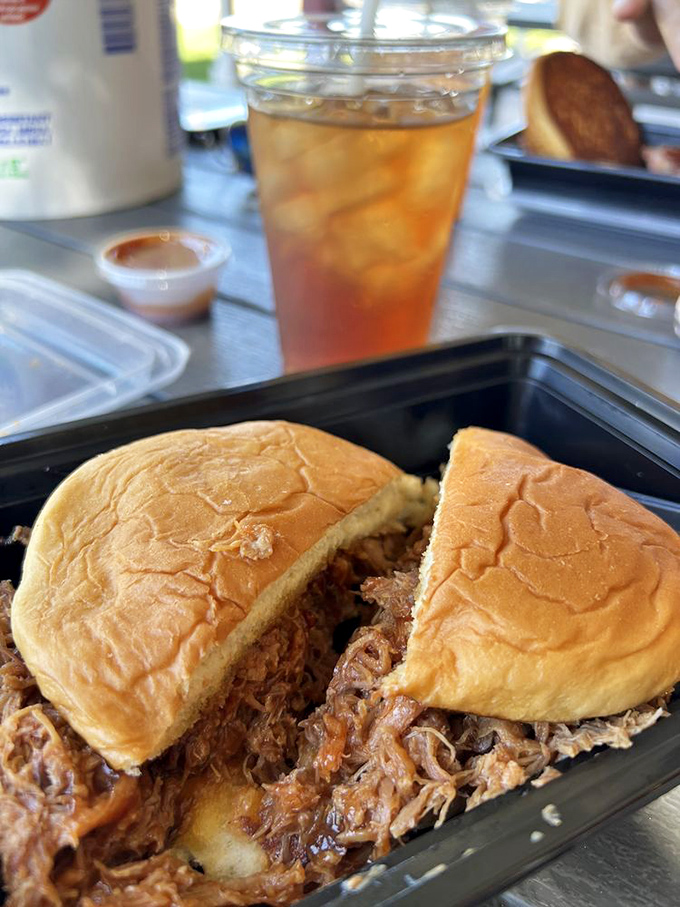 The sweet iced tea beside that overflowing pulled pork sandwich reminds you: someone in this kitchen understands the art of balance.