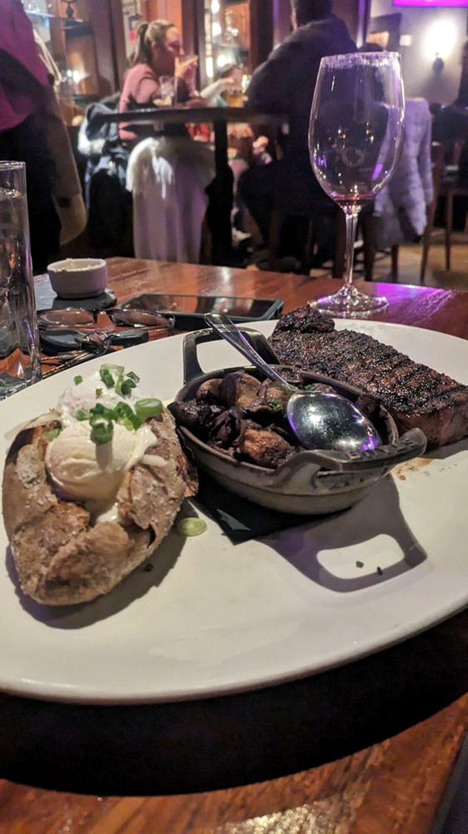 The holy trinity of steakhouse perfection: a seared masterpiece, green beans with personality, and potatoes that have achieved their cheesy destiny.