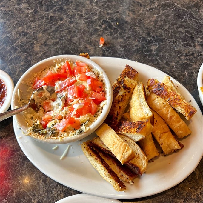 Artichoke dip that bridges the gap between "sharing plate" and "I might fight you for the last bite," served with perfectly grilled bread soldiers.