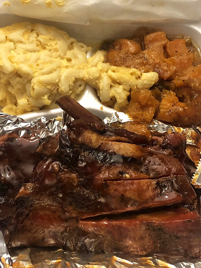 The holy trinity of comfort: fall-off-the-bone ribs, creamy mac and cheese, and candied yams. This isn't a meal; it's a warm hug on a styrofoam plate.