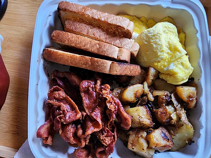 A breakfast trinity: crispy bacon, home fries with personality, and eggs that clearly came from chickens living their best lives.