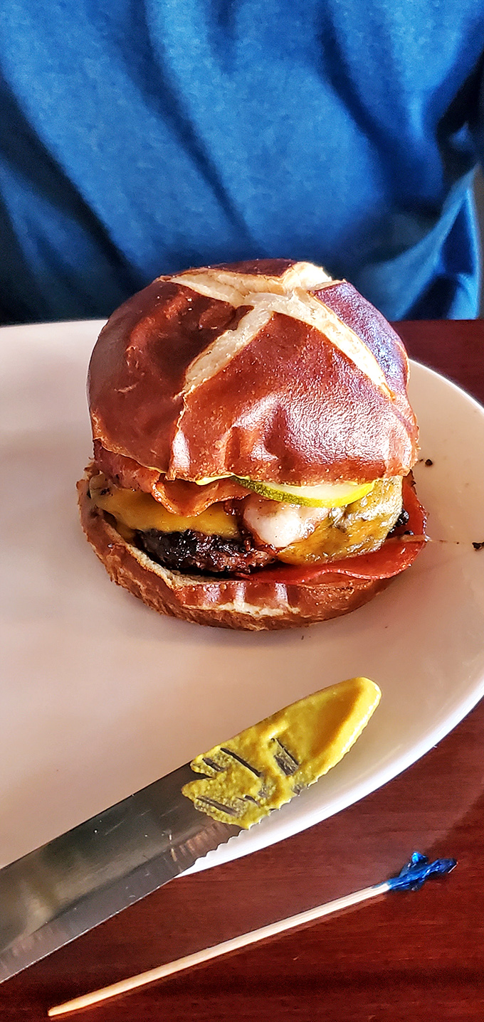 Served on a pretzel bun that glistens like it just won a beauty pageant, this burger demands both your attention and your appetite.
