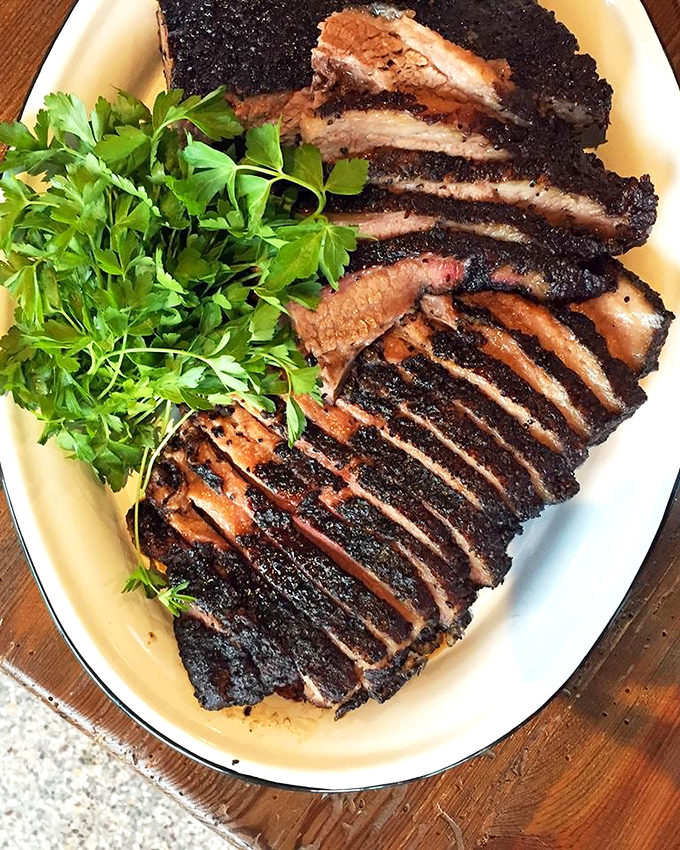 Sliced brisket with that glistening bark that barbecue dreams are made of. The parsley garnish isn't fooling anyone&mdash;this plate is gloriously, unapologetically carnivorous.