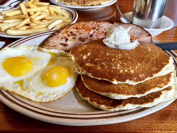 The breakfast trinity: golden pancakes, sunny-side-up eggs, and ham that makes you wonder why you ever bothered with fancy brunches.