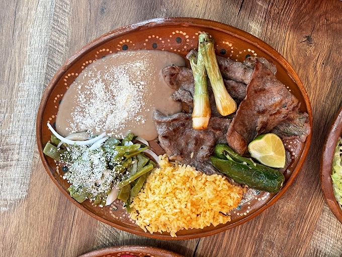 Carne asada doesn't get more authentic than this&mdash;charred perfection, vibrant rice, and grilled vegetables on traditional pottery that tells its own story.