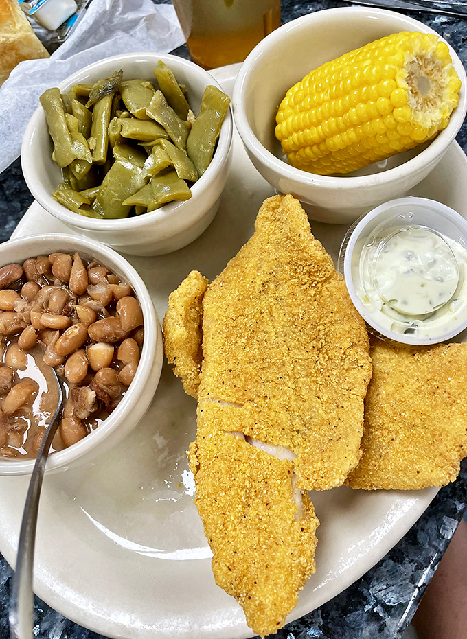 This cornmeal-crusted catfish isn't just dinner—it's Southern poetry on a plate, with sides that could star on their own menu.