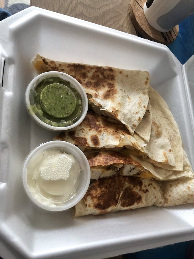 Quesadillas done right&mdash;crispy exterior, molten cheese interior, with sides of cool sour cream and that vibrant green sauce for perfect temperature contrast.