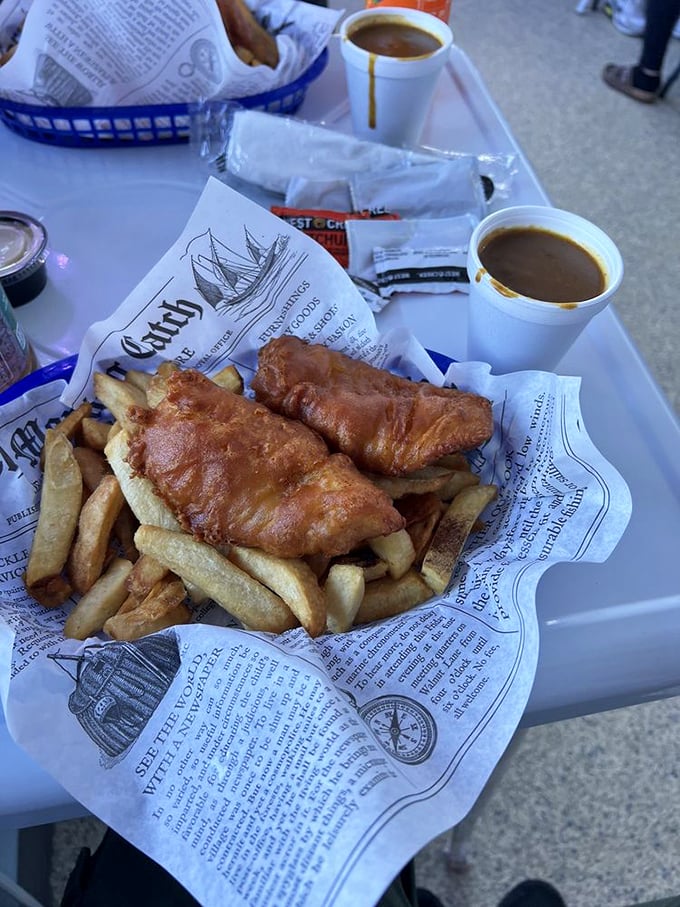 Newspaper-wrapped fish and chips with curry sauce cups standing by &ndash; this isn't just lunch, it's a cultural exchange program for your taste buds.