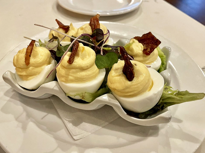 The deviled egg &ndash; reimagined. Creamy filling piped with precision, crowned with crispy bacon and delicate greens. Simplicity and decadence on one plate.