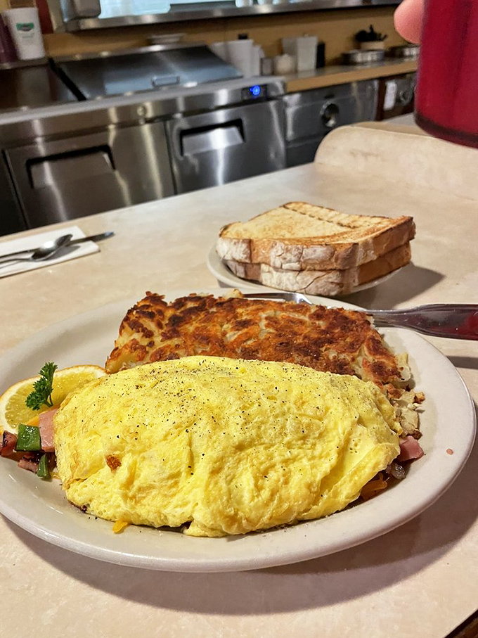 An omelet so fluffy it might float away if not anchored by perfectly crisp hash browns. The toast stands guard, ready for action.