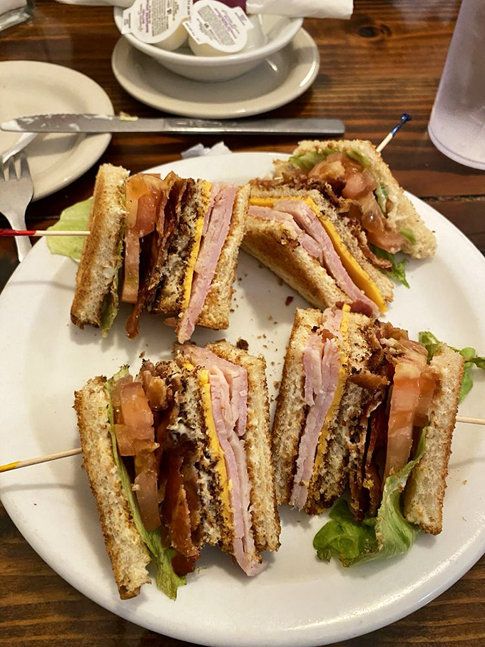 Not just any club sandwich—this towering masterpiece requires a strategic approach and the jaw flexibility of a python.