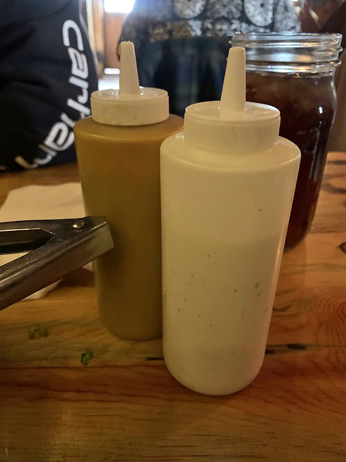 Simple squeeze bottles hold the secret weapons of flavor&mdash;ranch dressing and honey mustard stand ready for duty on the wooden battlefield.