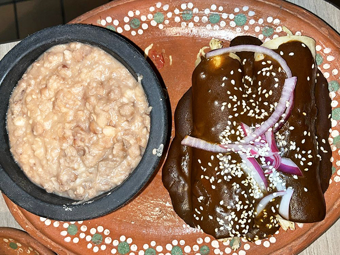 Rich, complex mole sauce adorns these enchiladas while refried beans stand guard—a duo that's been making taste buds swoon since forever.