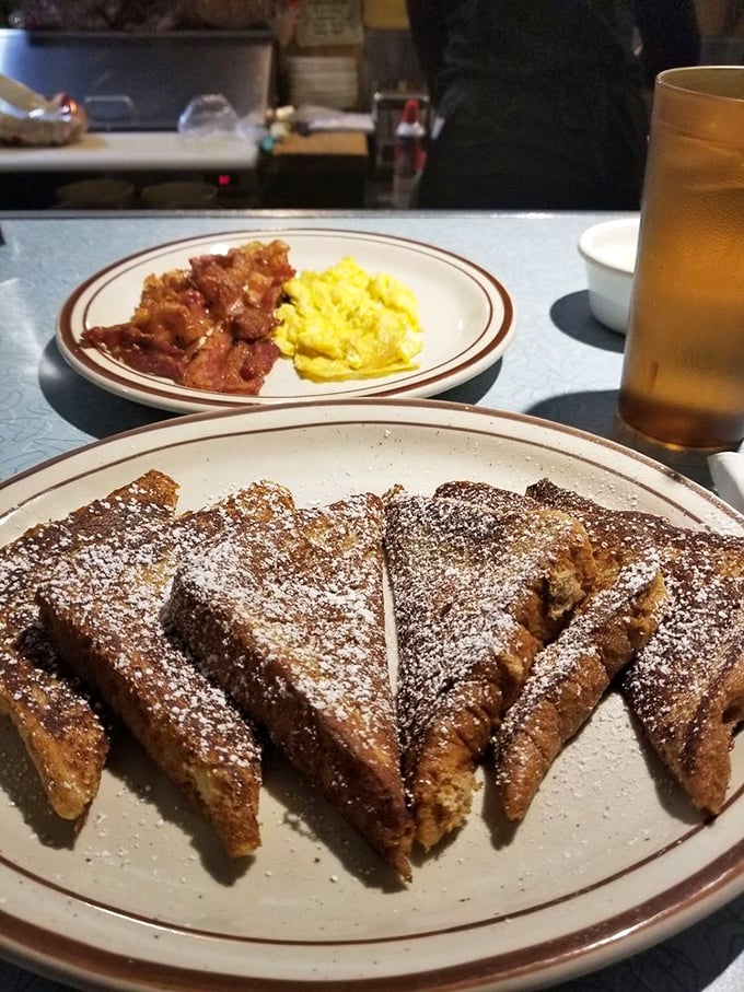 French toast dusted with powdered sugar like fresh snow, accompanied by bacon that's achieved that mythical balance between crispy and chewy.