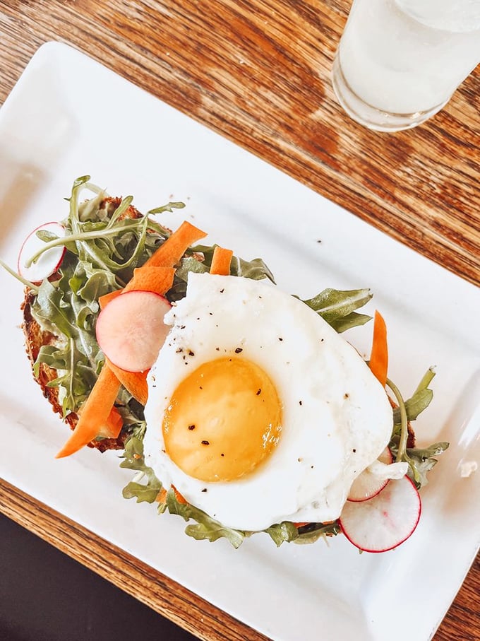 The perfect breakfast composition: sunny-side up egg perched atop fresh greens and vegetables like nature's most beautiful morning masterpiece.
